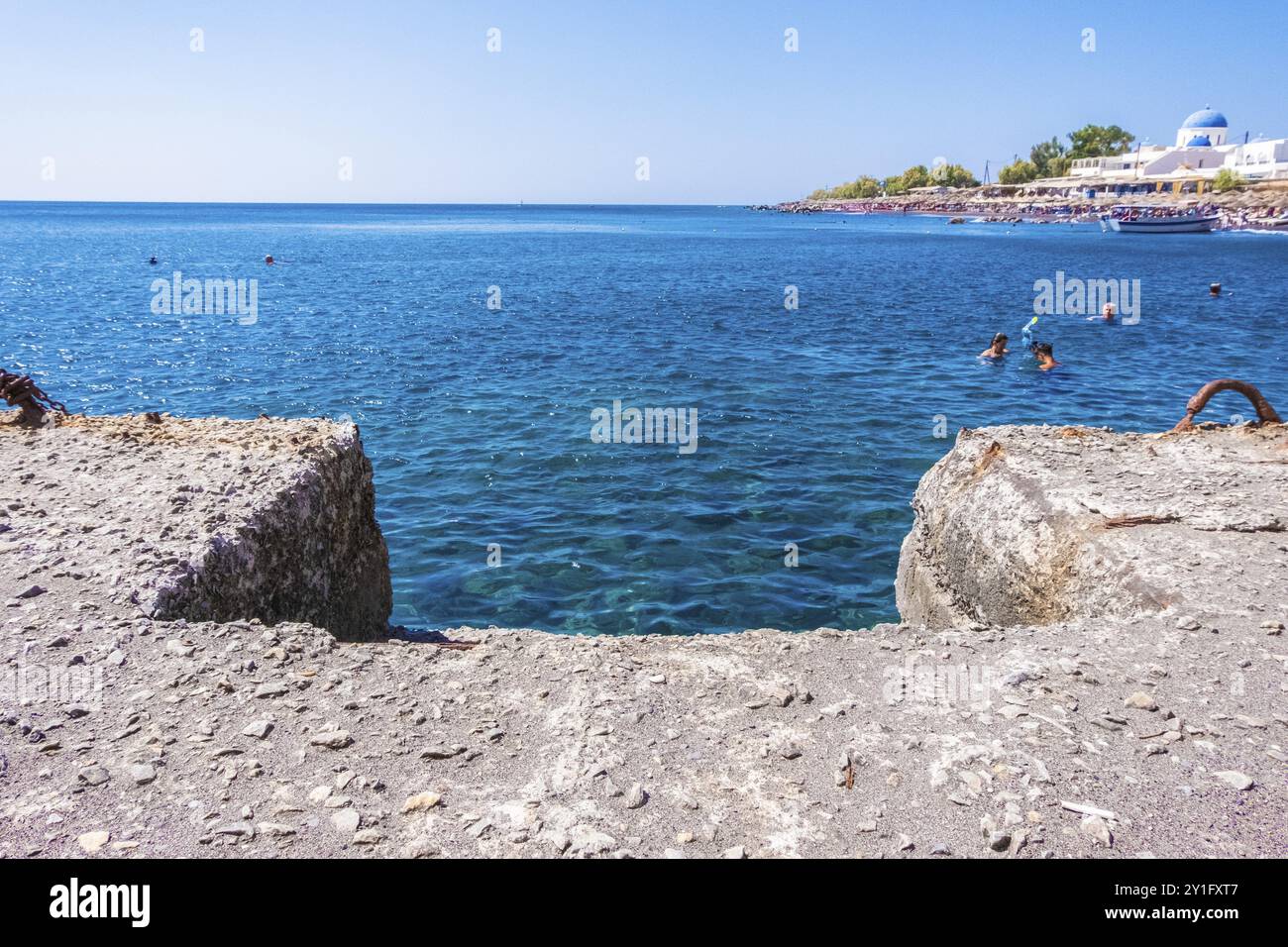 A basic concrete jetty stretches into the Aegean Sea from the coast of ...