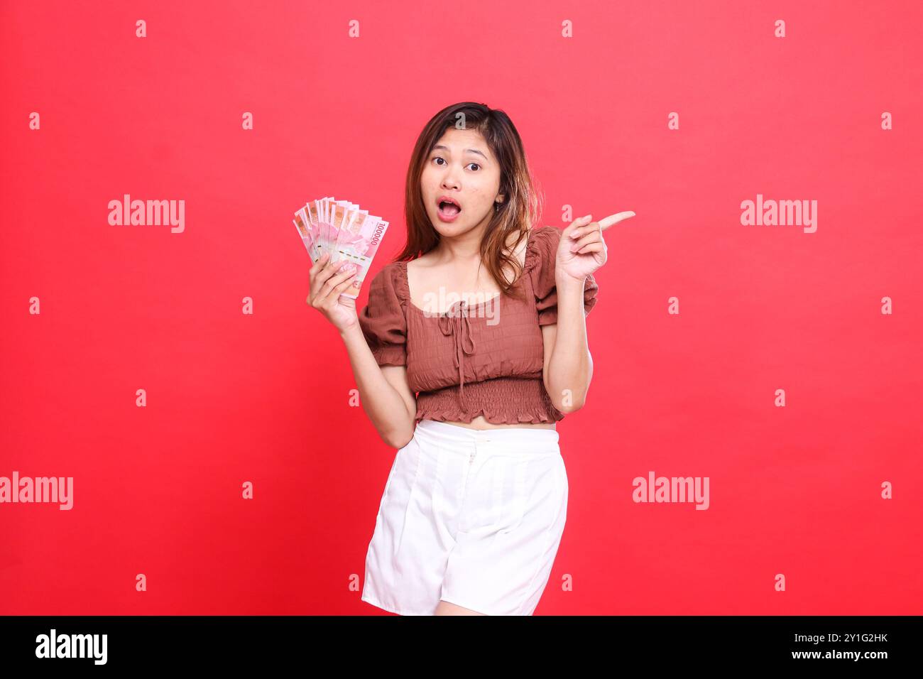 The expression of a shocked Asian woman holding rupiah money while ...