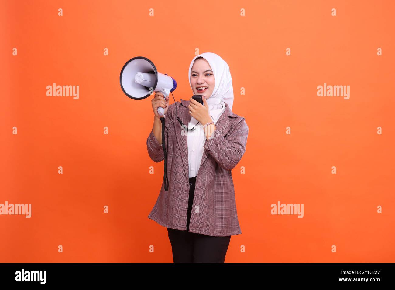Cheerful young indonesia woman in hijab facing right sideways shouting ...