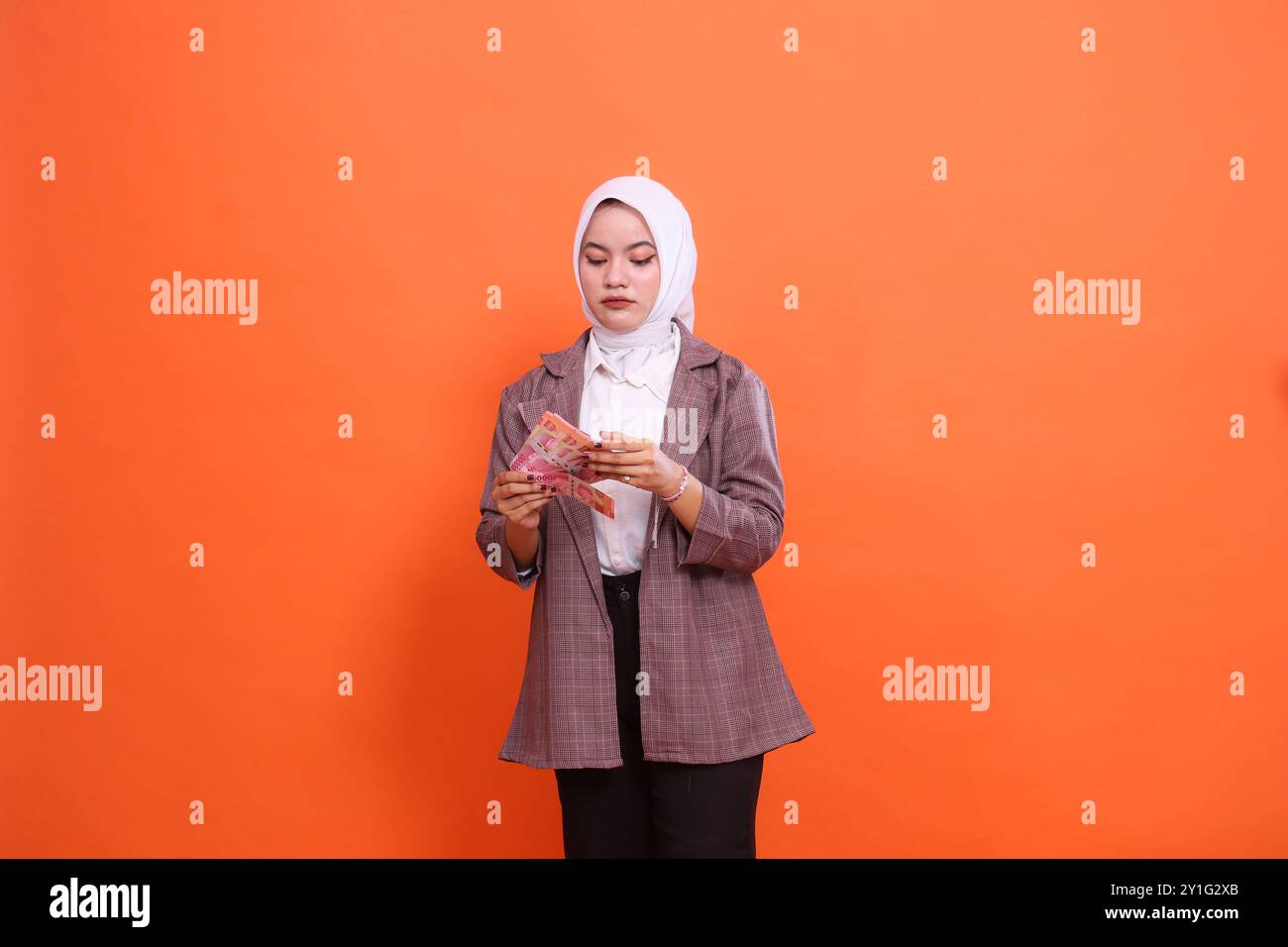 Excited beautiful Asian woman wearing hijab holding and counting ...