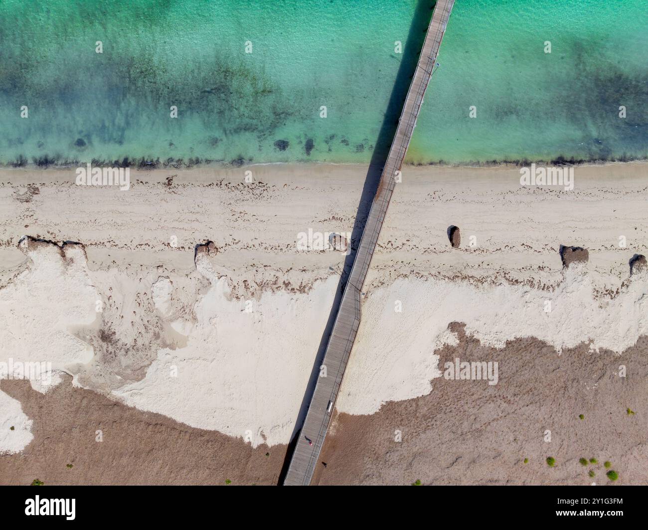 Aerial view of a long narrow jetty out overa white sand beach and the ...
