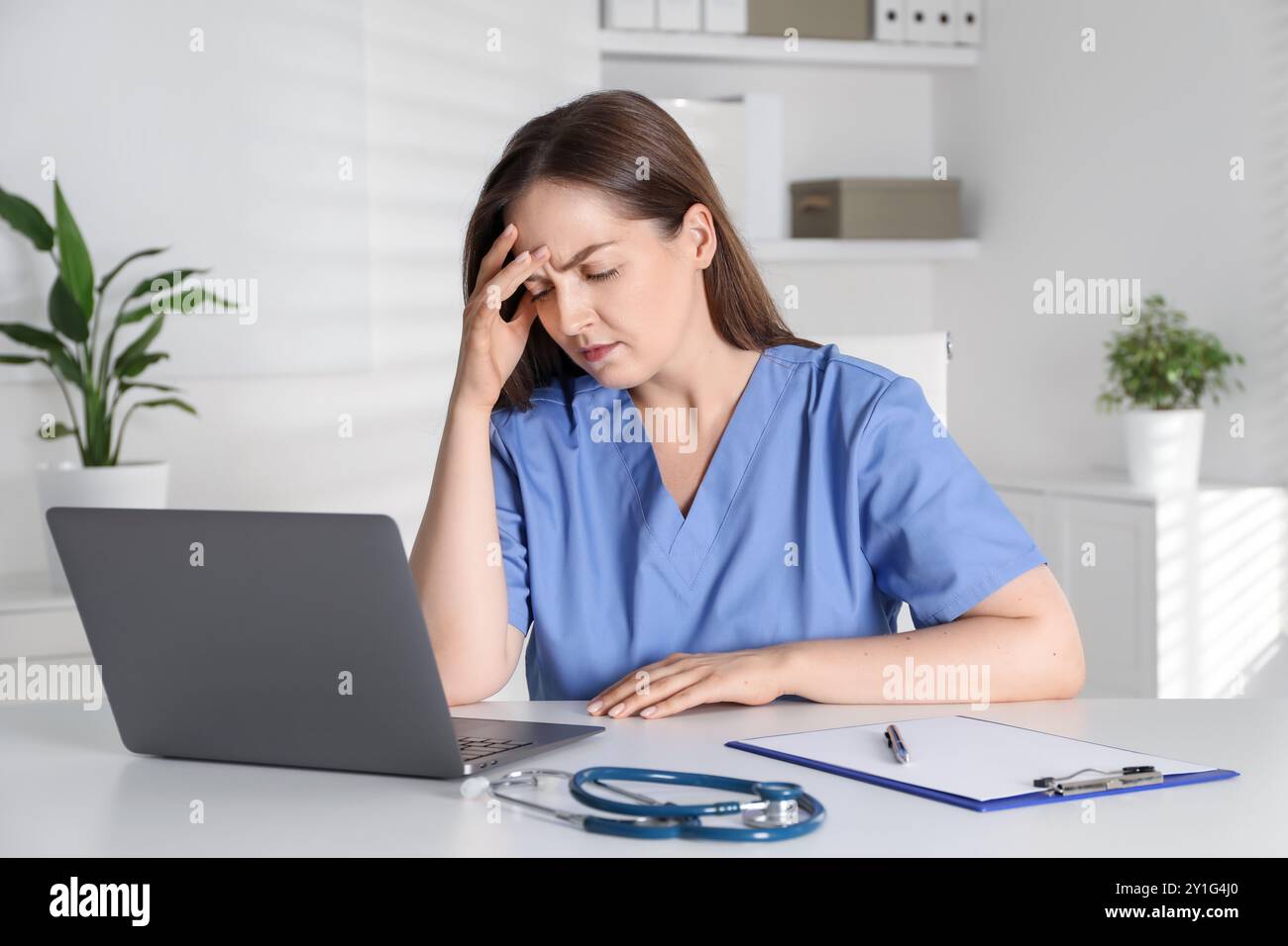 Tired nurse working at desk in hospital Stock Photo - Alamy