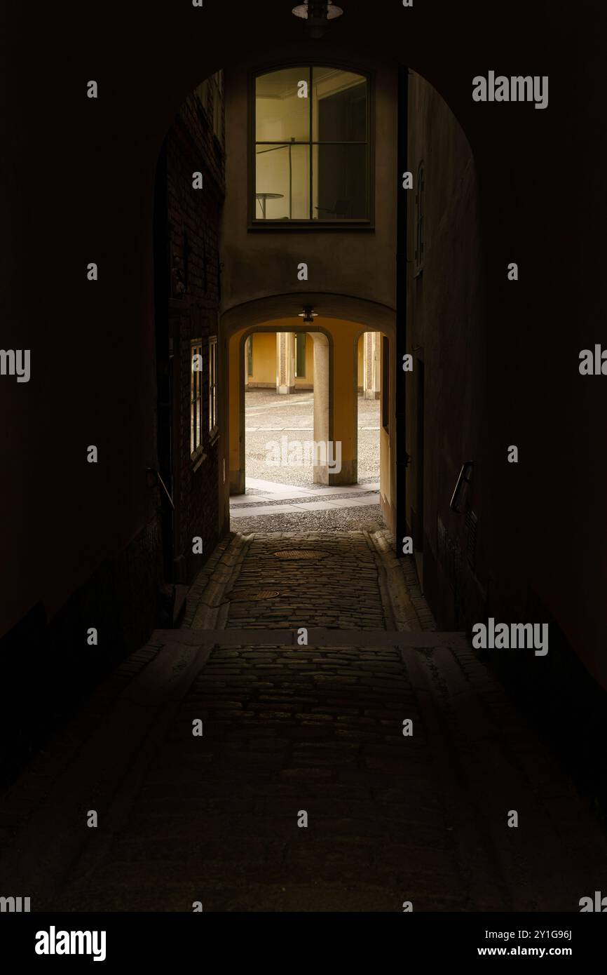 View through a dark archway into a cobblestone courtyard Stock Photo ...