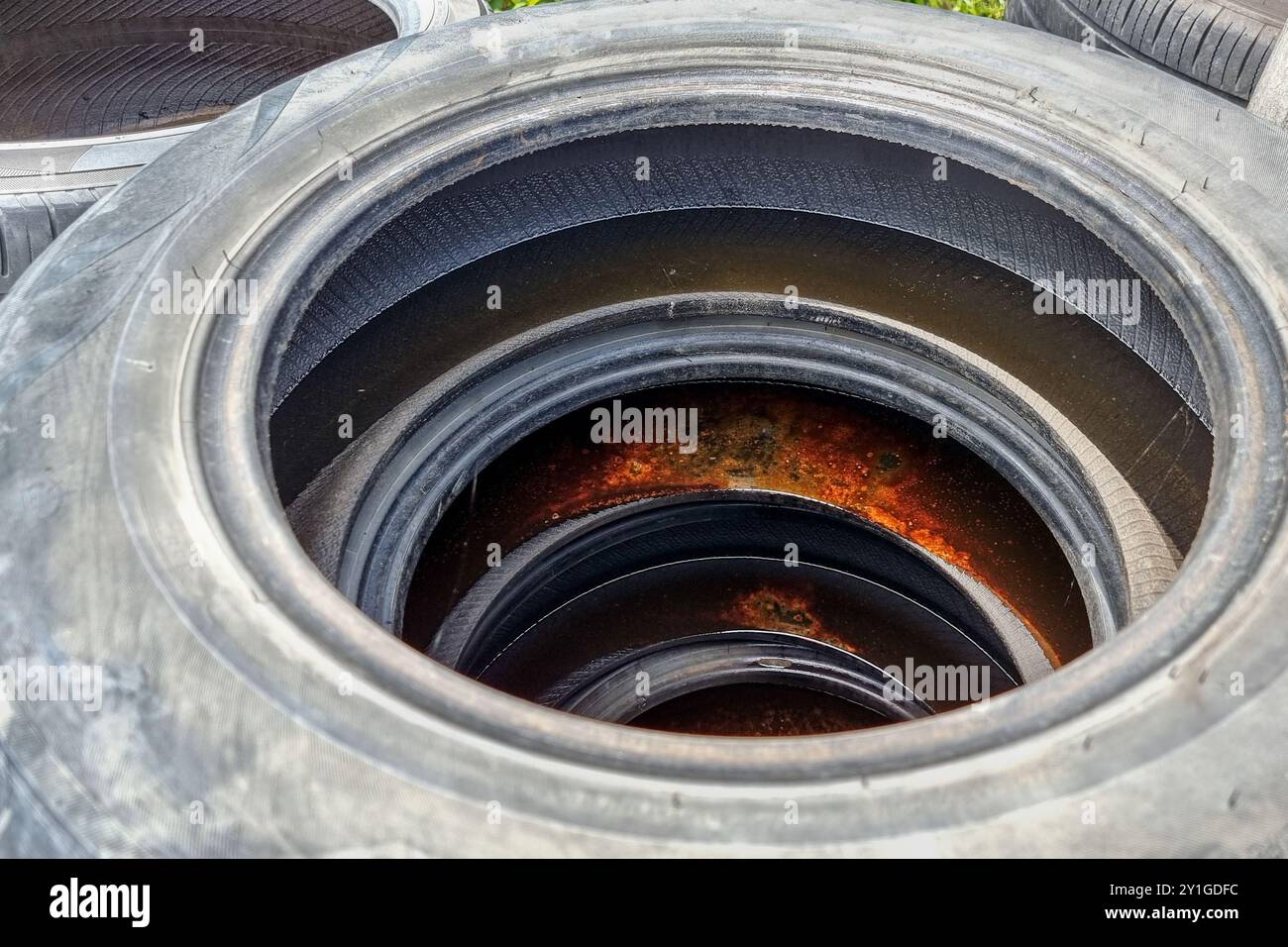 Closeup on stack of old and used tires with rain water and become ...