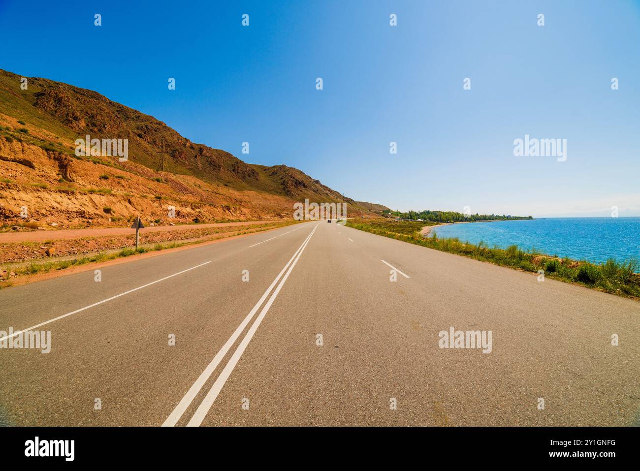 asphalt interstate road between yellow sedimentary rock mountain and ...