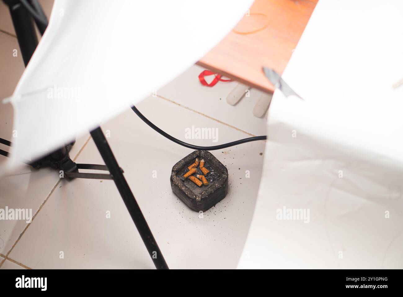 A small black stone or clay pot with several cigarette butts inside ...