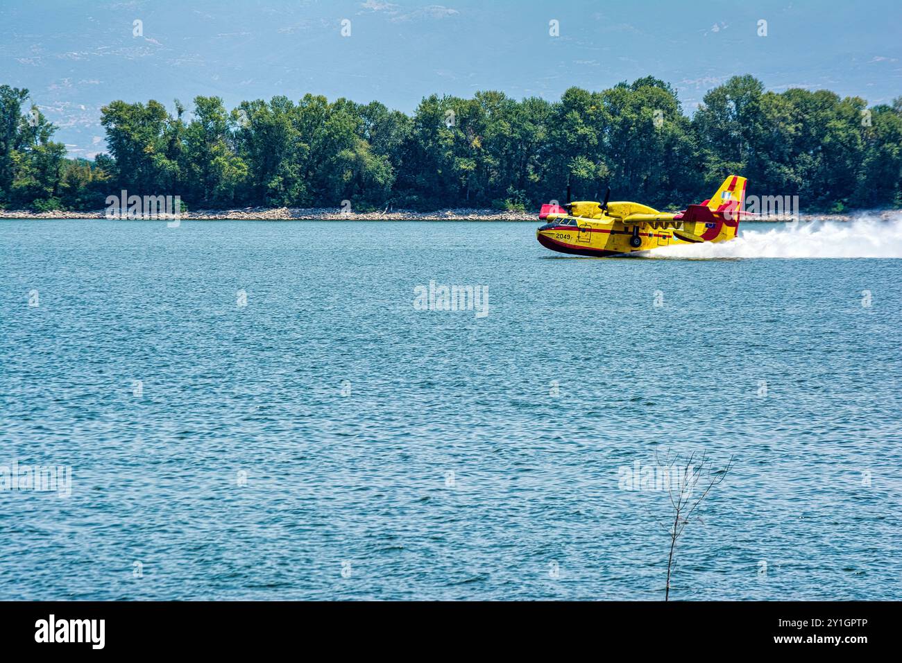 A yellow firefighting plane skims the surface of Lake Kerkini in Greece ...