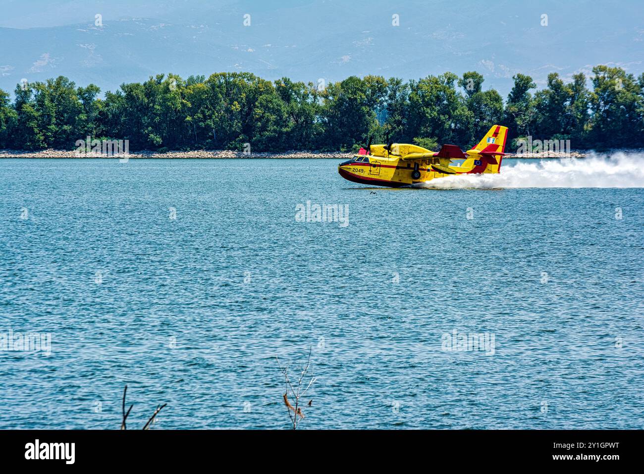 A yellow firefighting plane skims the surface of Lake Kerkini in Greece ...
