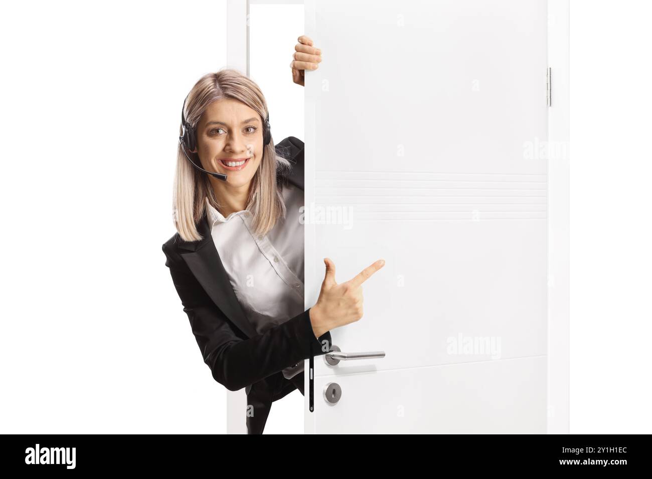 Female call operator with a headset standing behind a door and pointing ...