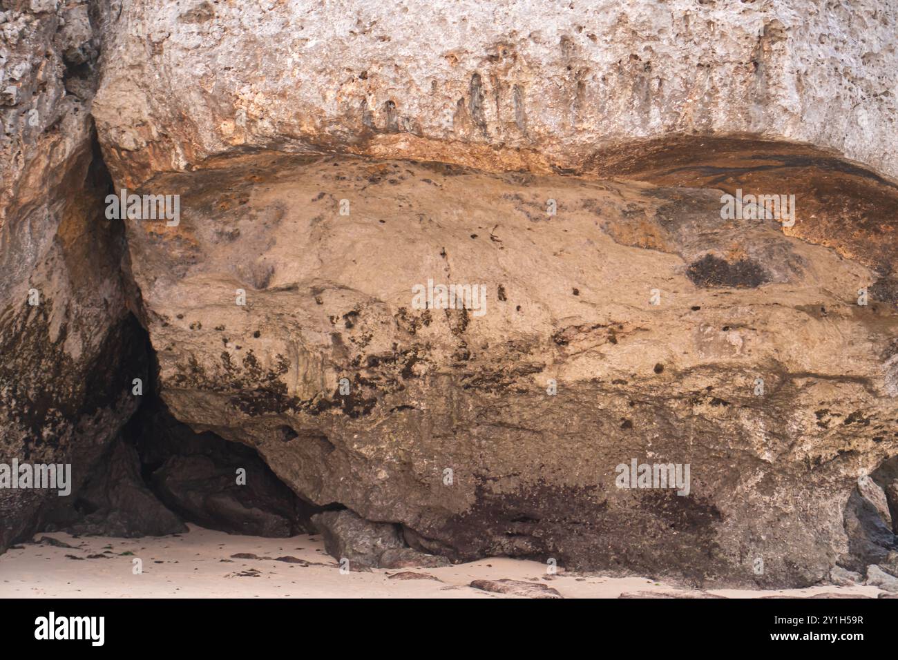 A close-up view of a rocky cave entrance on a beach, showcasing ...