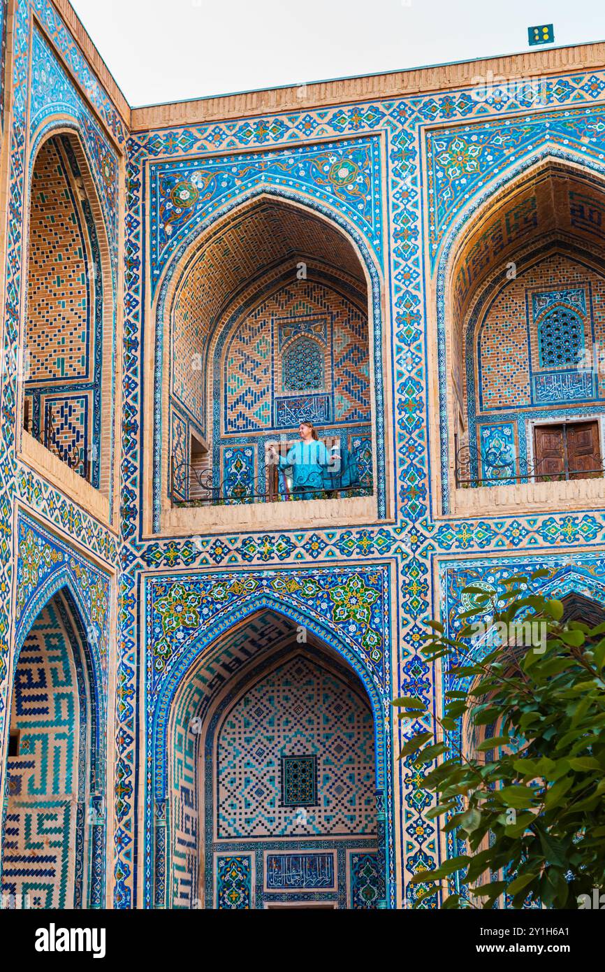Woman in blue traditional clothing in the courtyard of the Ulugbek ...