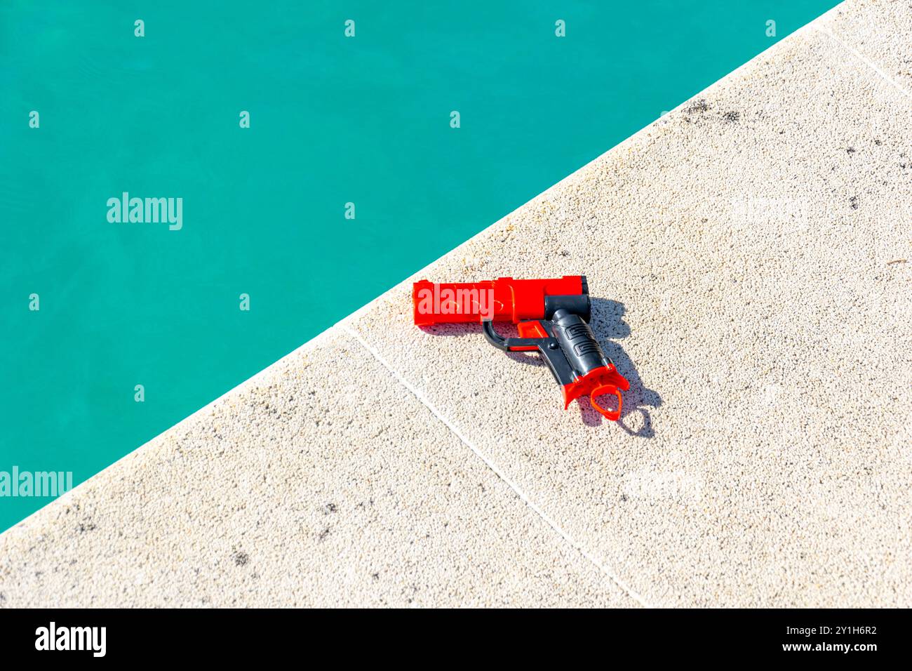 red plastic gun on the edge of a swimming pool in summer, holidays ...