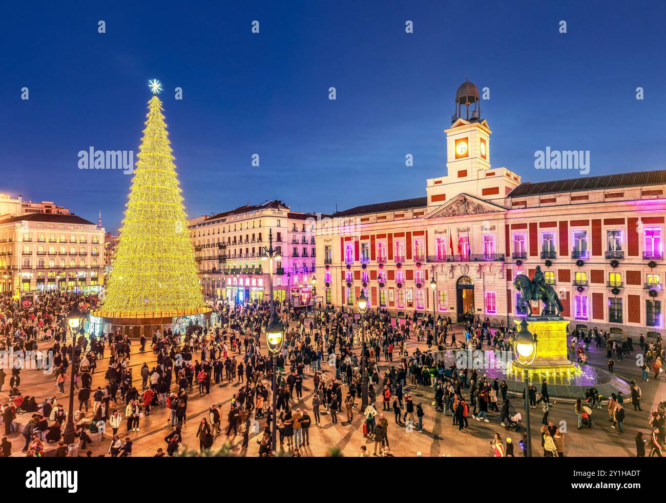 Festive crowd gathers around a great golden Christmas tree in the ...