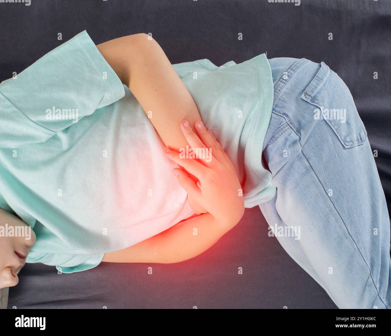 A seven-year-old girl lies and holds her sore stomach. Concept of ...