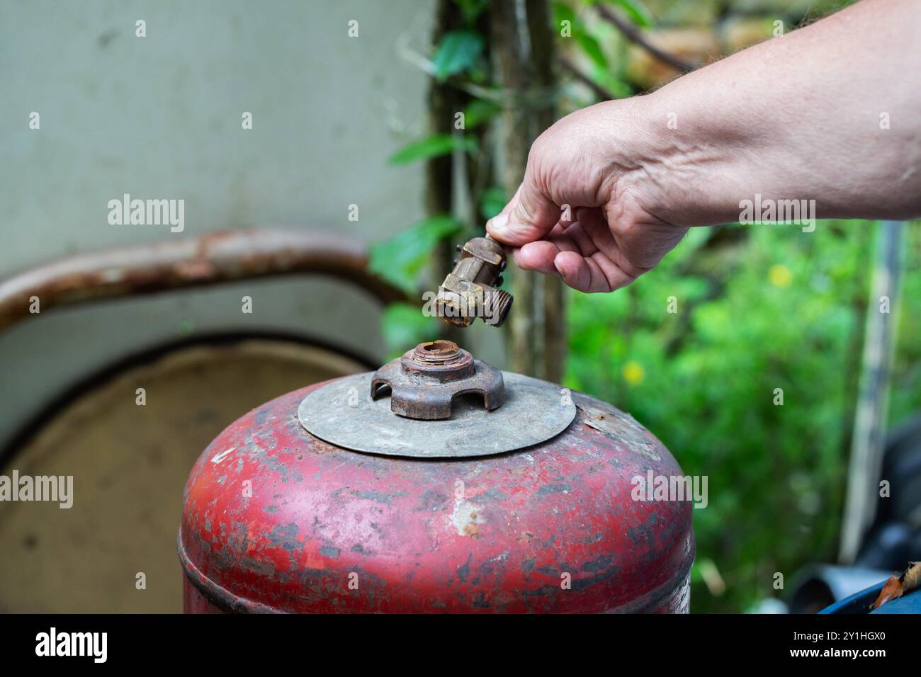 A broken valve of a gas cylinder in a hand against the background of a ...