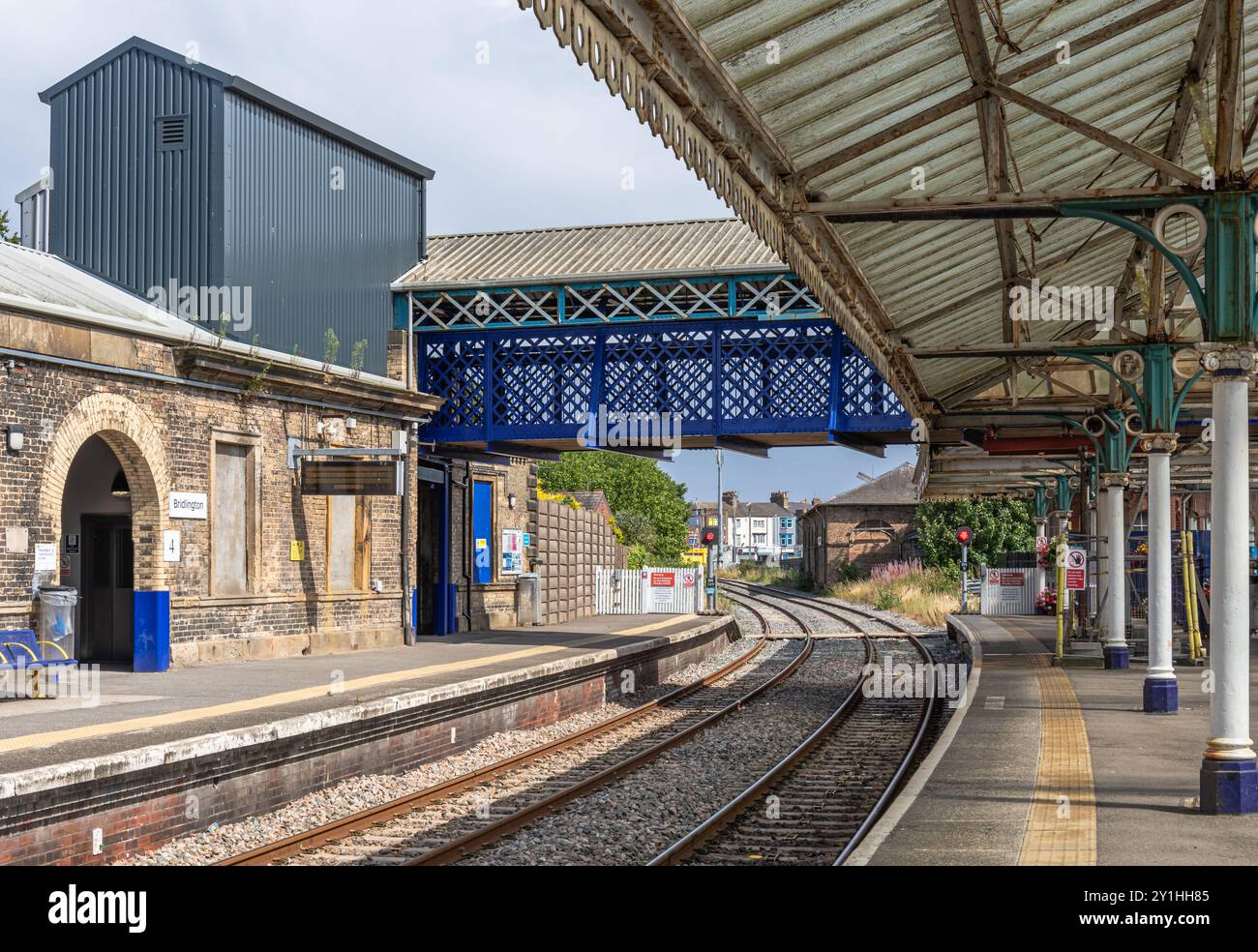Historic railway station platform with rails curving into the distance ...