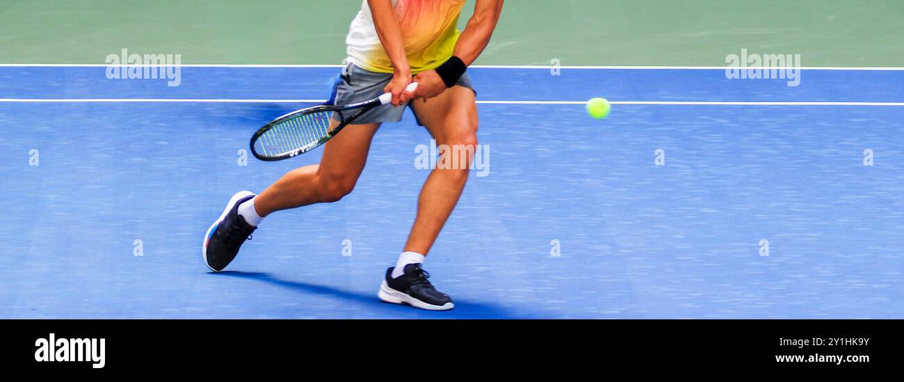 Side view of a Male tennis player aggressively swinging with two hands ...