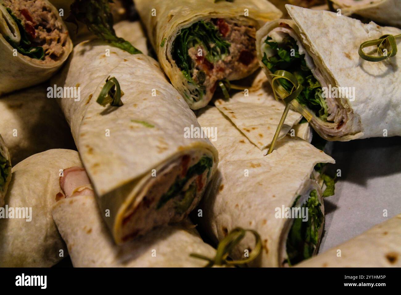 A close-up view of rolled wraps filled with greens, meats, and spreads ...
