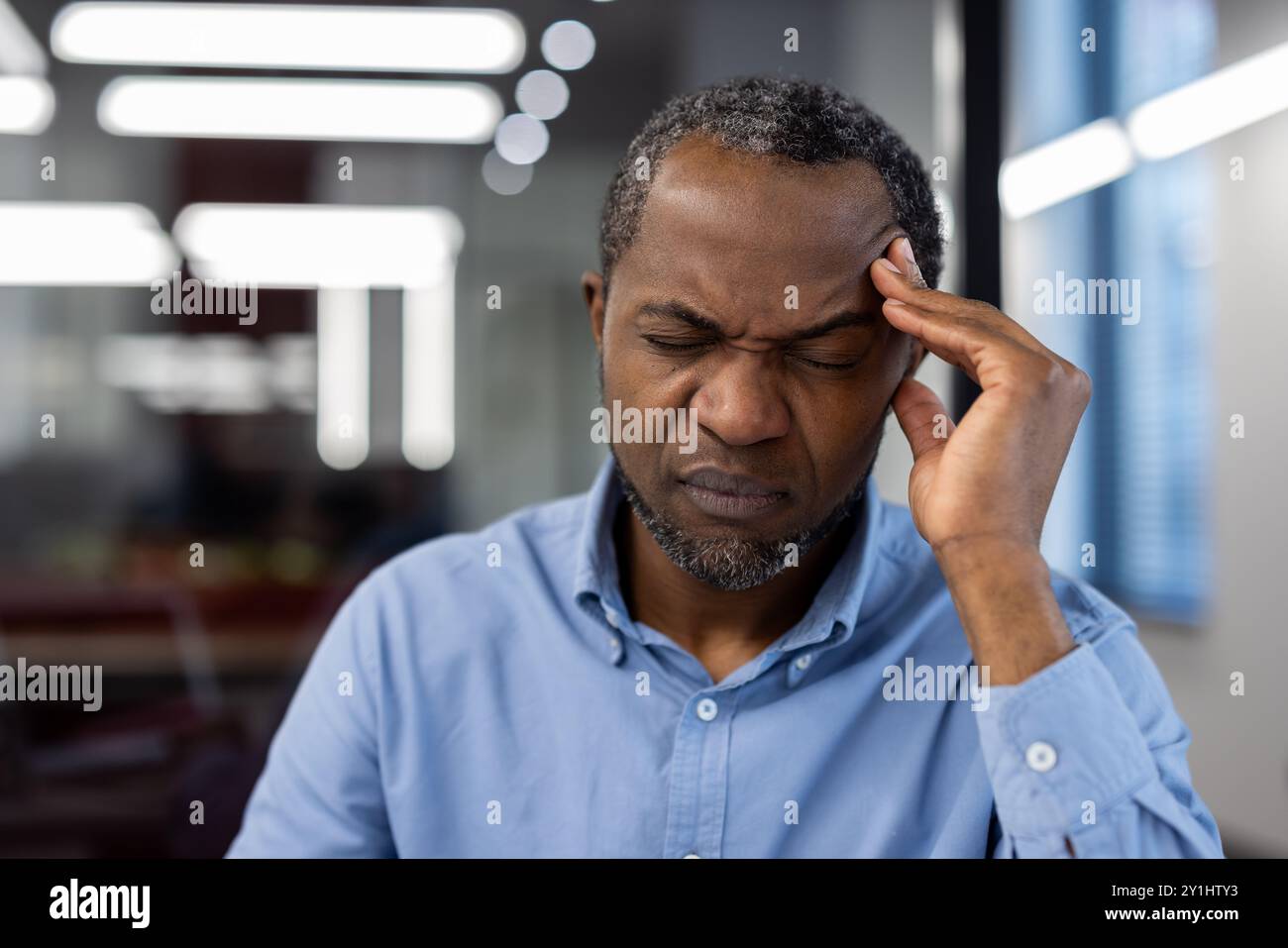 Businessman experiencing stress, holding head in frustration at work ...