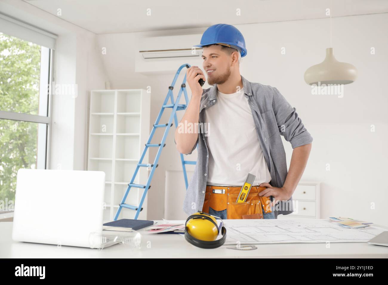 Male contractor talking on radio transmitter in room Stock Photo - Alamy
