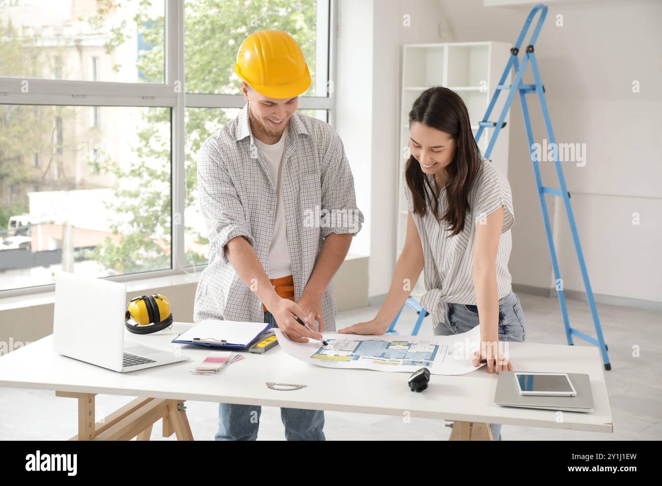 Male contractor with client discussing house plan in room Stock Photo ...