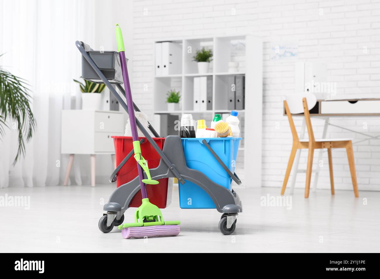 Janitor's trolley with cleaning supplies and floor mop in office Stock ...