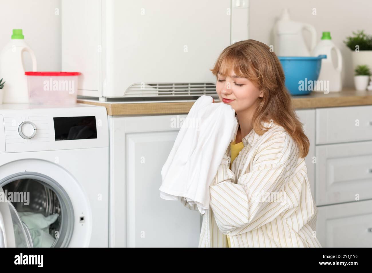 Young woman smelling clean laundry from washing machine at home Stock ...