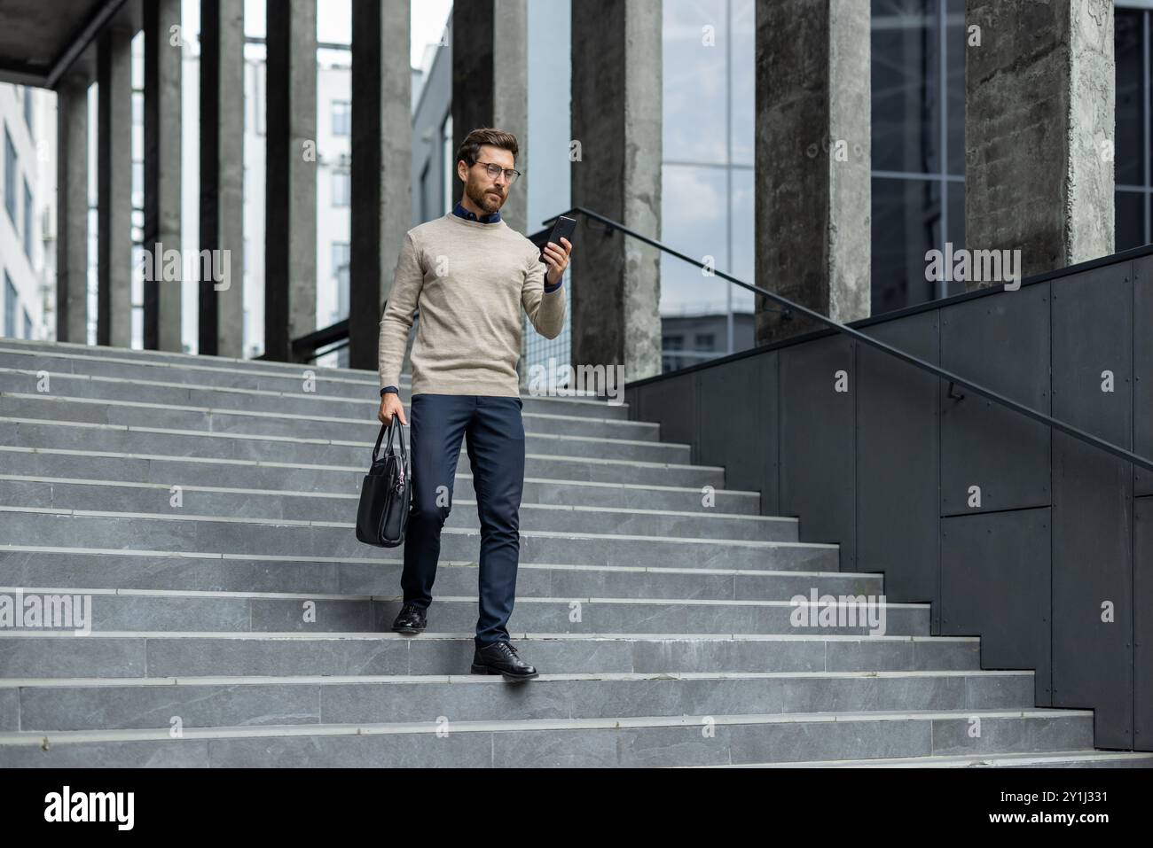Business professional in modern outfit walking down city stairs using ...