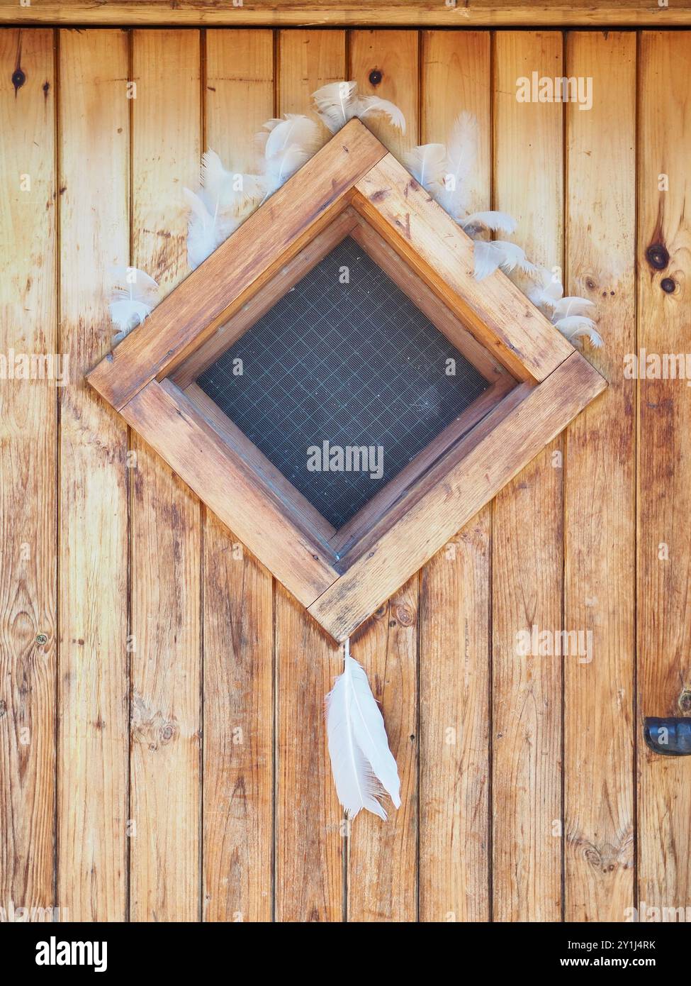 A close-up image of a wooden door featuring a diamond-shaped window ...