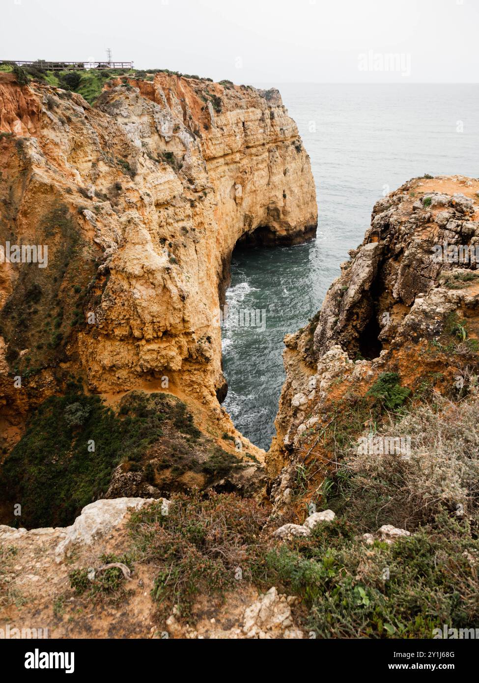Rocky coastal cliffs with a natural arched shape, overlooking the clear ...
