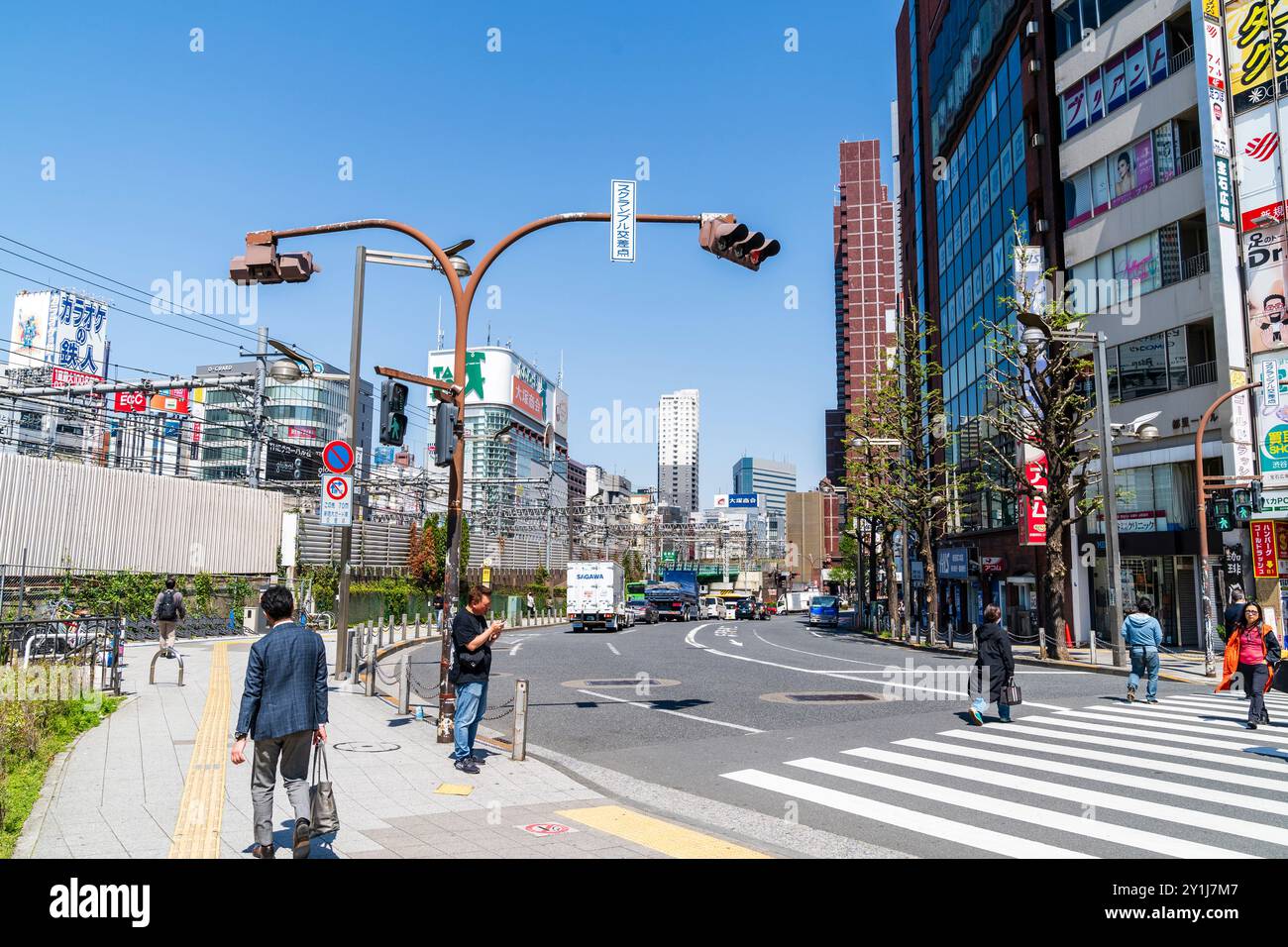View along Shinjuku dori, road, on a hot springtime day. Railway ...