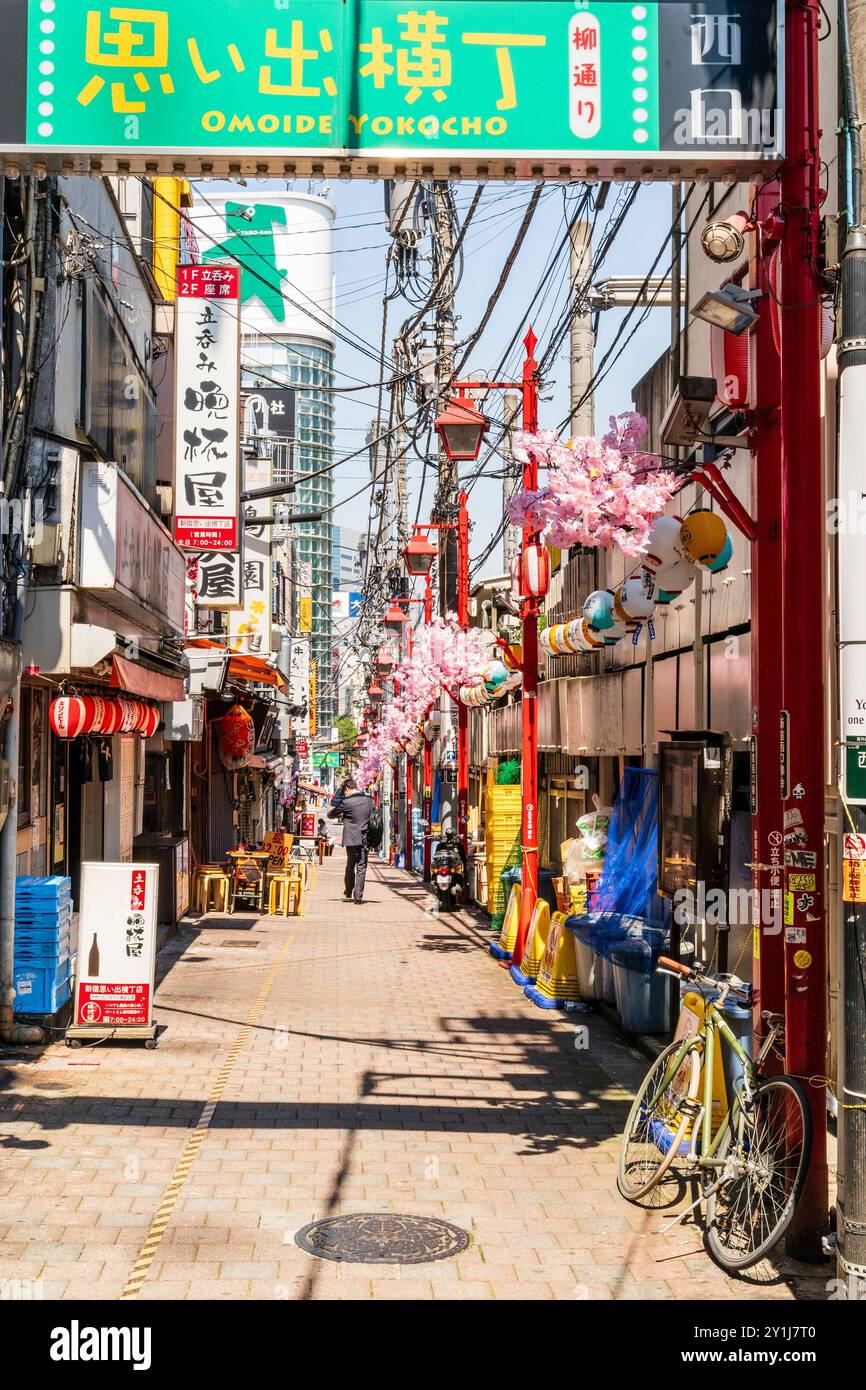 Salaryman walking along Omoide Yokocho, a lively and nostalgic alley ...
