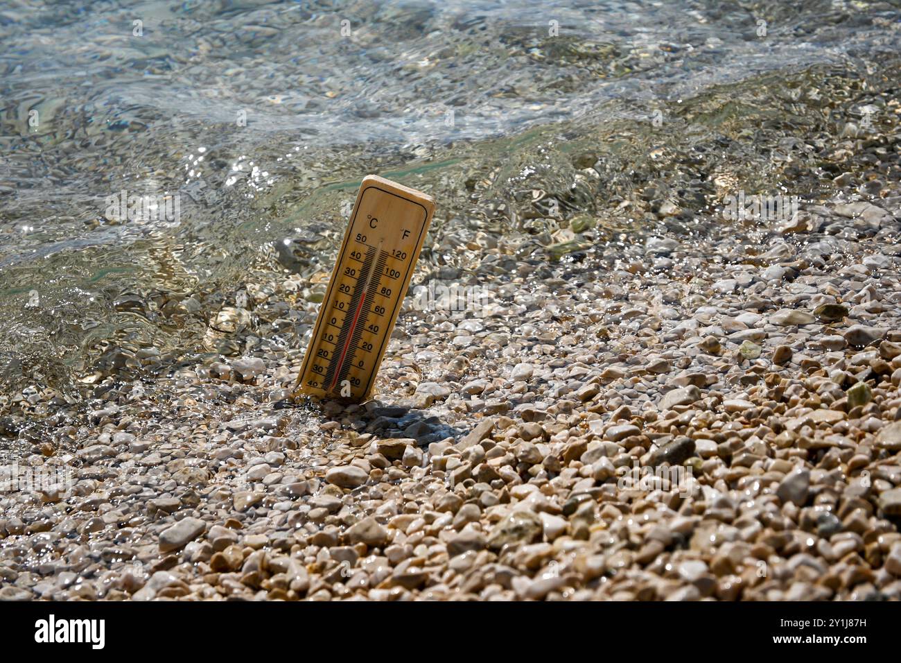 Wooden thermometer measuring increasing temperature of sea water during ...