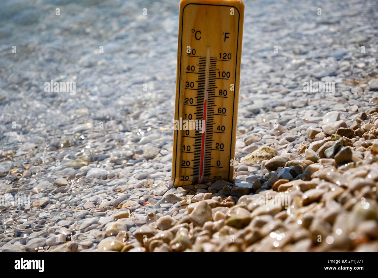 Wooden thermometer measuring increasing temperature of sea water during ...