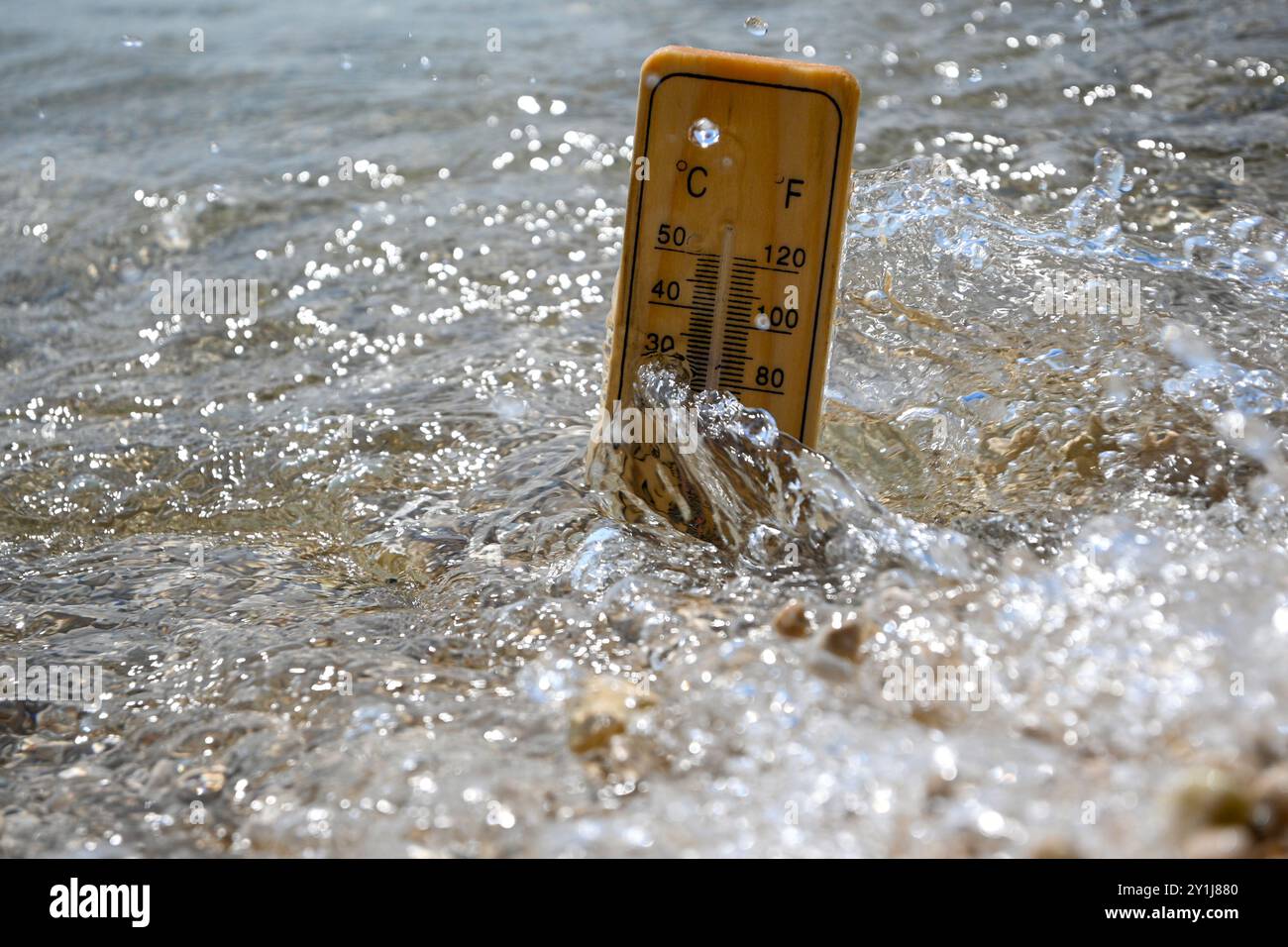 Wooden thermometer measuring increasing temperature of sea water during ...