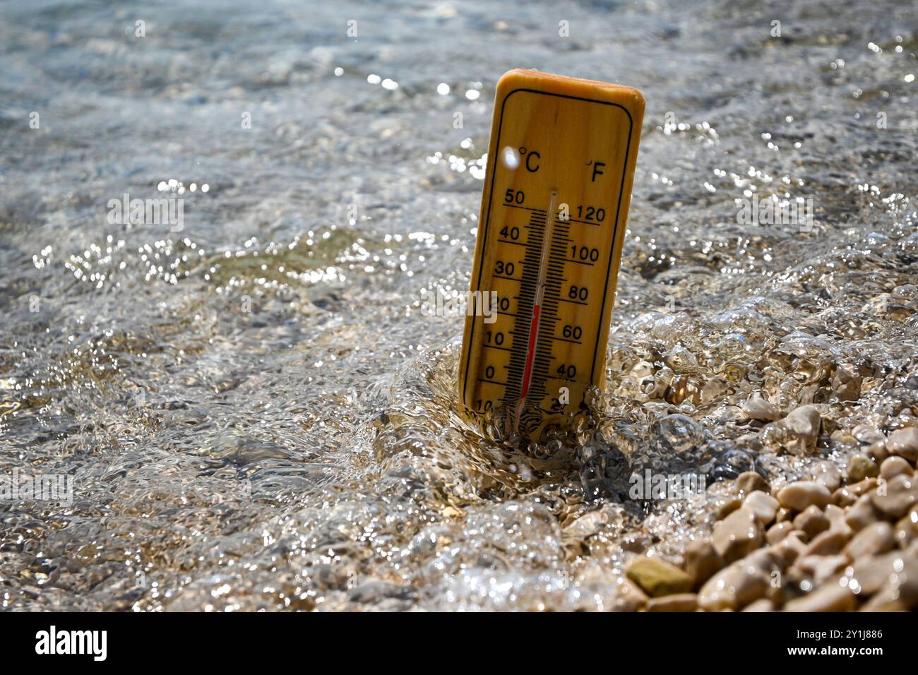 Wooden thermometer measuring increasing temperature of sea water during ...