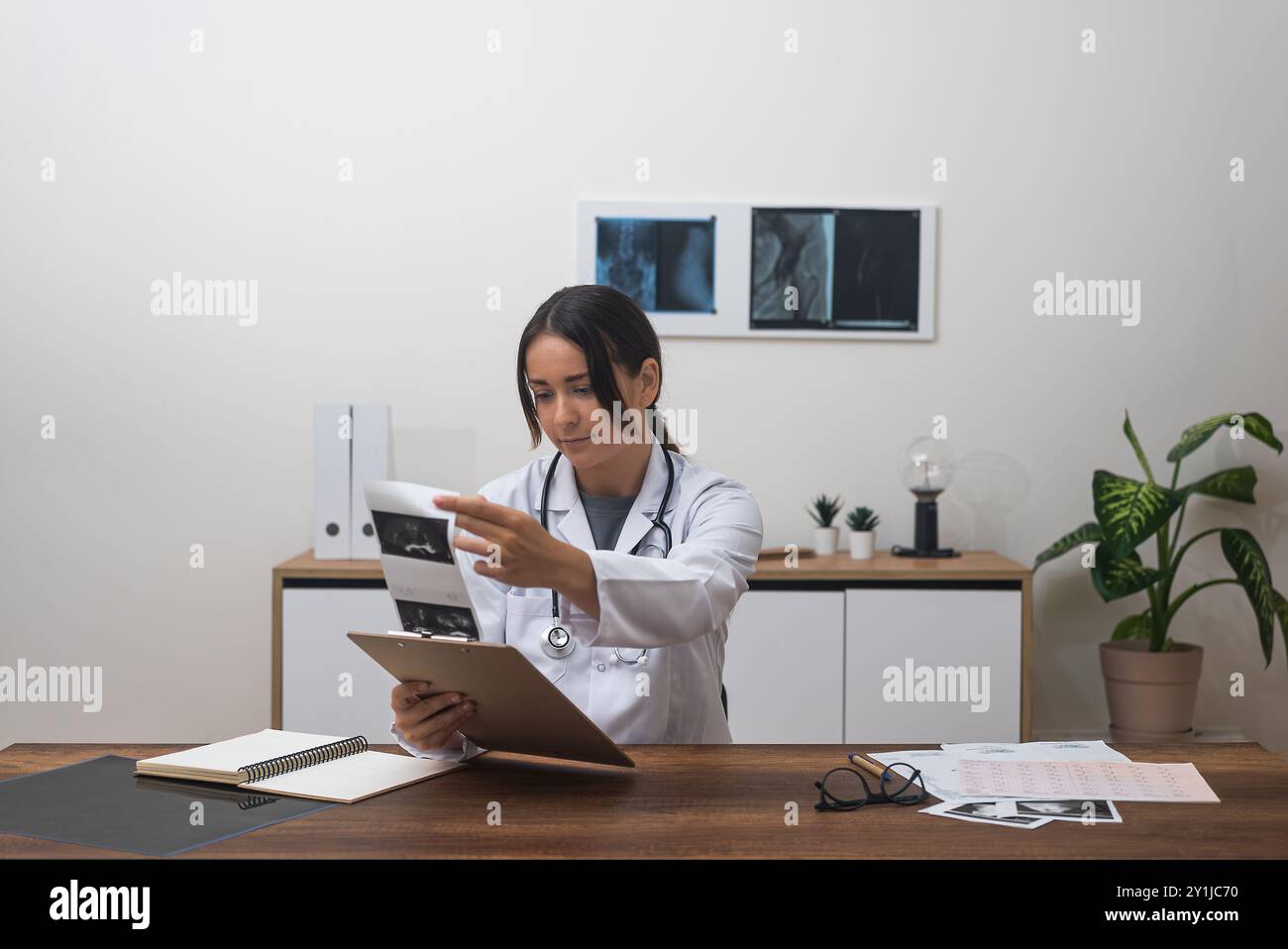 female doctor reviews patient test results at her clinic desk ...