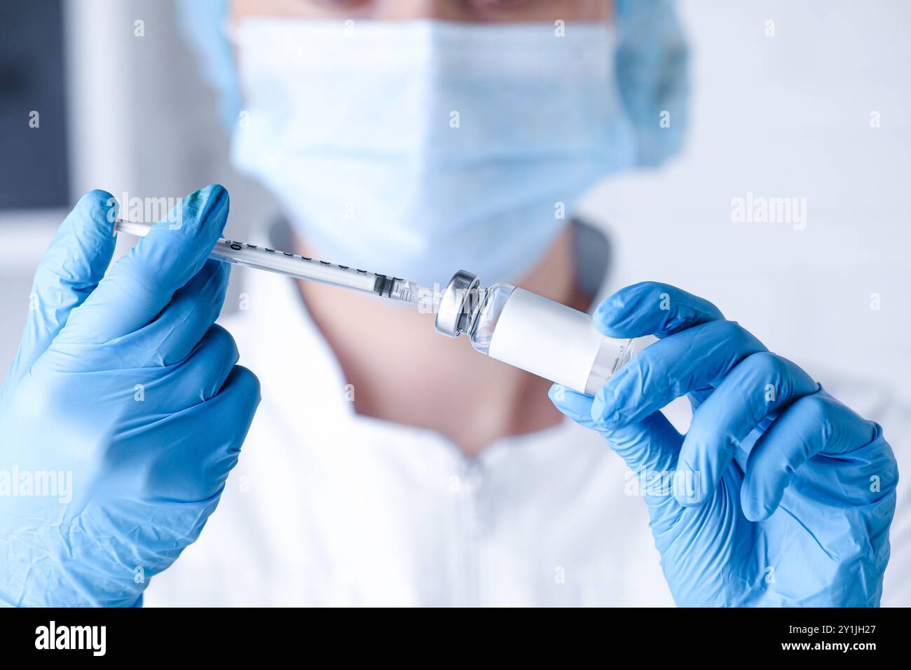 Nurse filling syringe with medication from glass vial in hospital ...