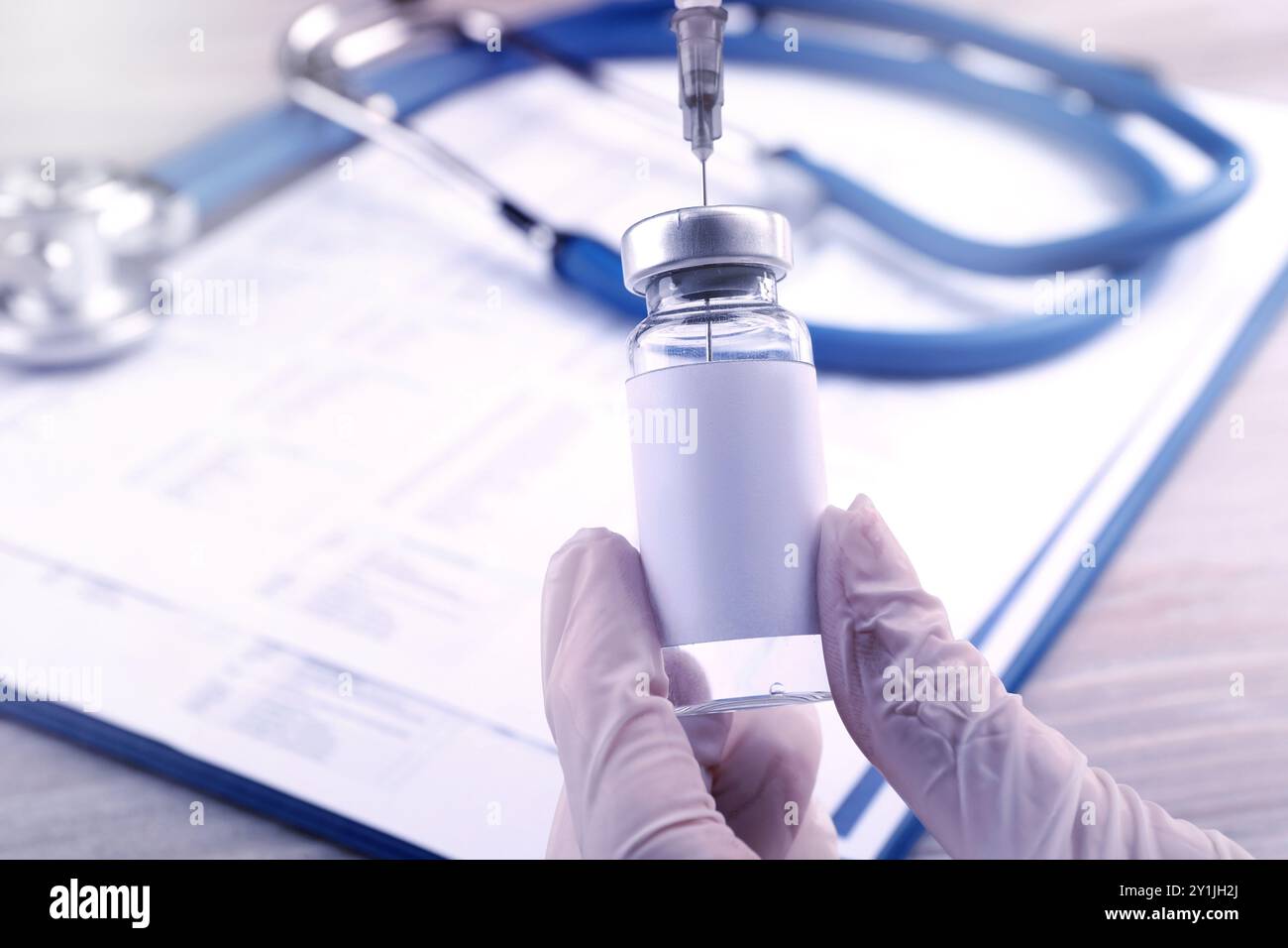 Nurse filling syringe with medication from vial over table, closeup ...