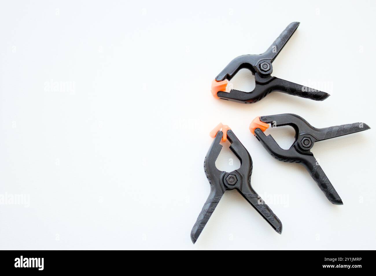 Three black plastic spring clamps over white background with copy space ...