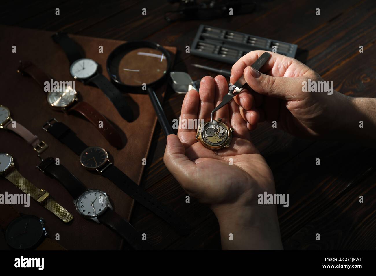 Man fixing mechanism of vintage wrist watch at wooden table, closeup ...