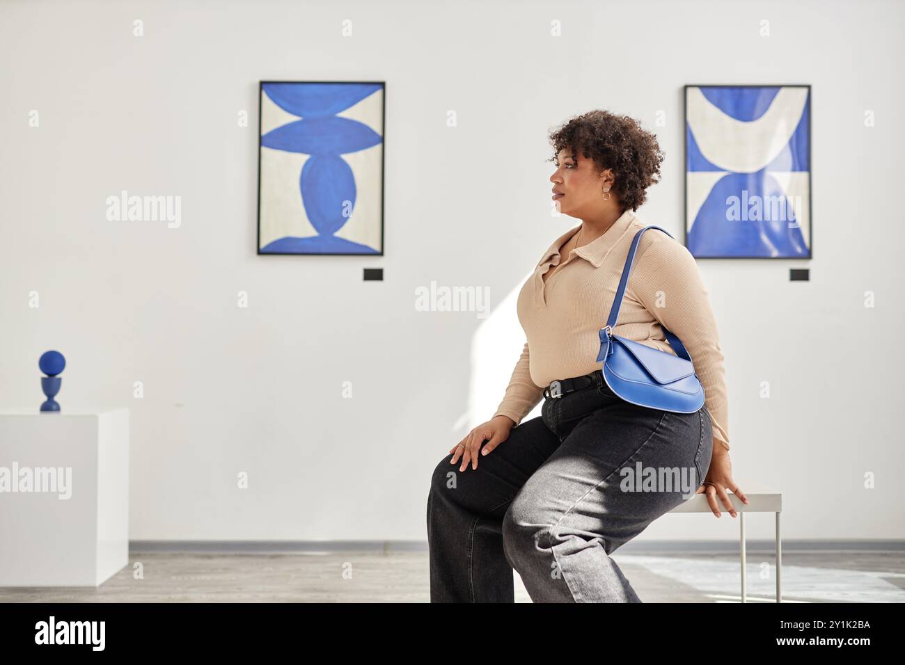 Minimal side view of Black woman looking at abstract art paintings and ...