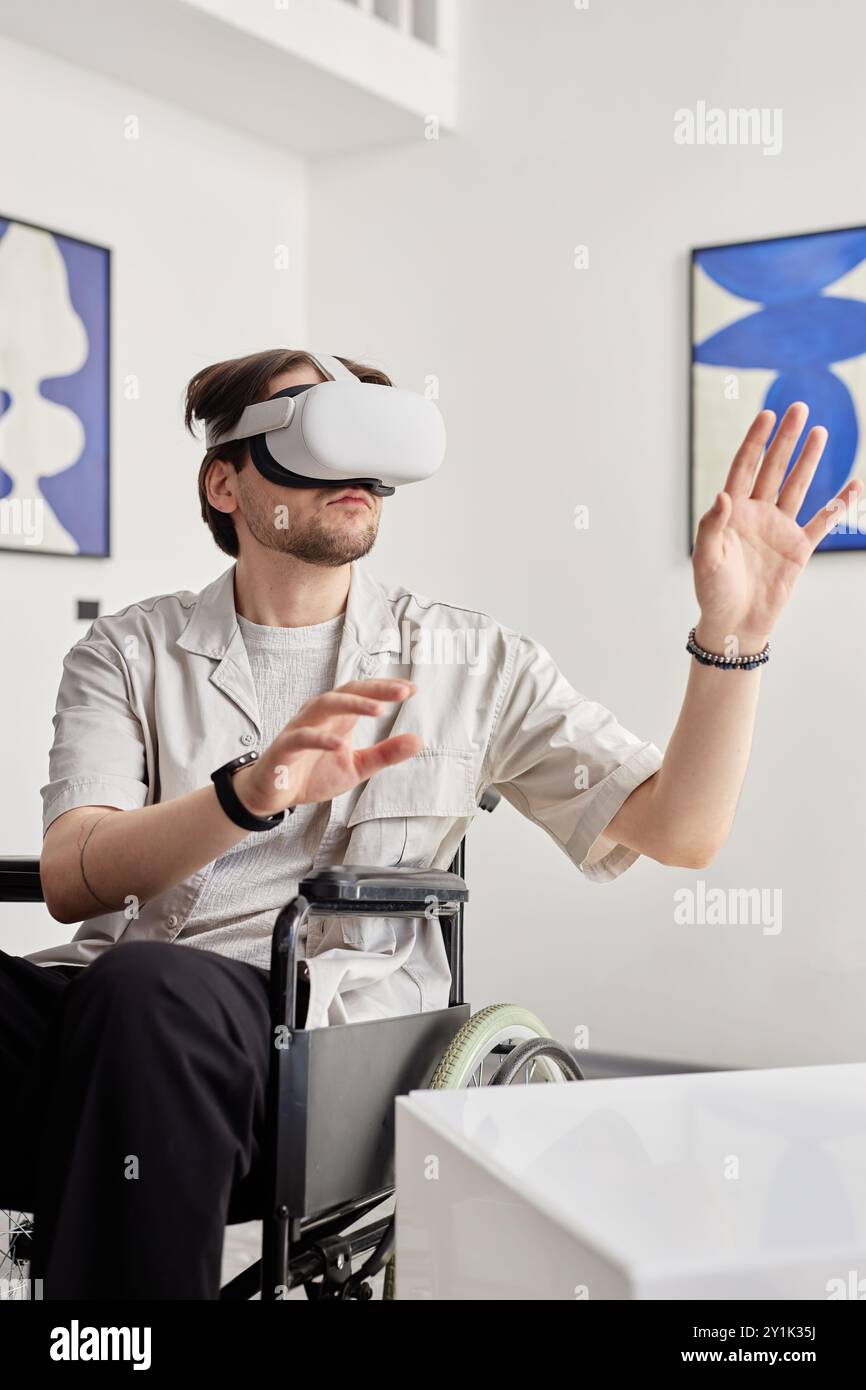 Vertical portrait of man with disability using VR technology and ...