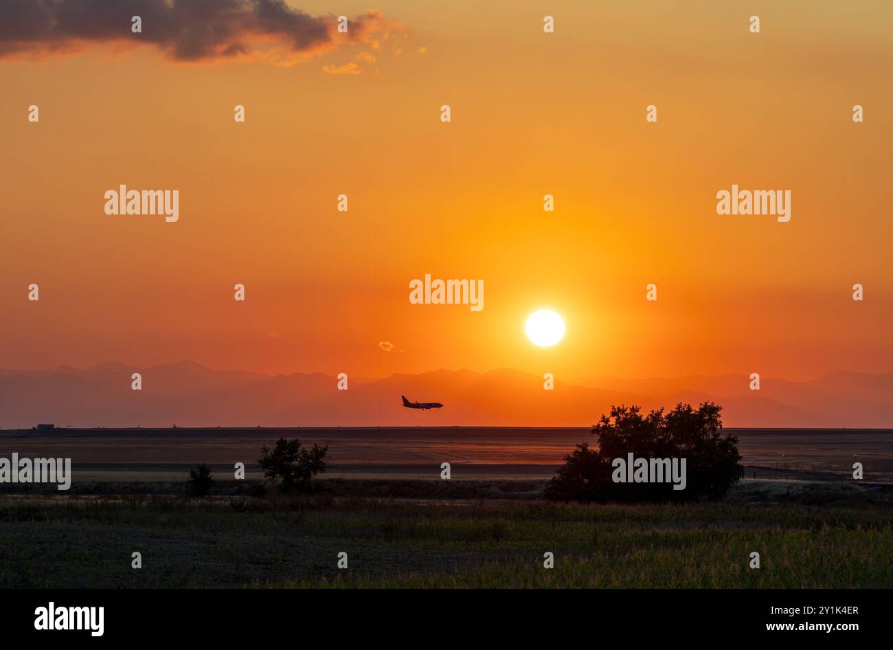 An airplane flying in the sunset sky above the Colorado prairies with ...
