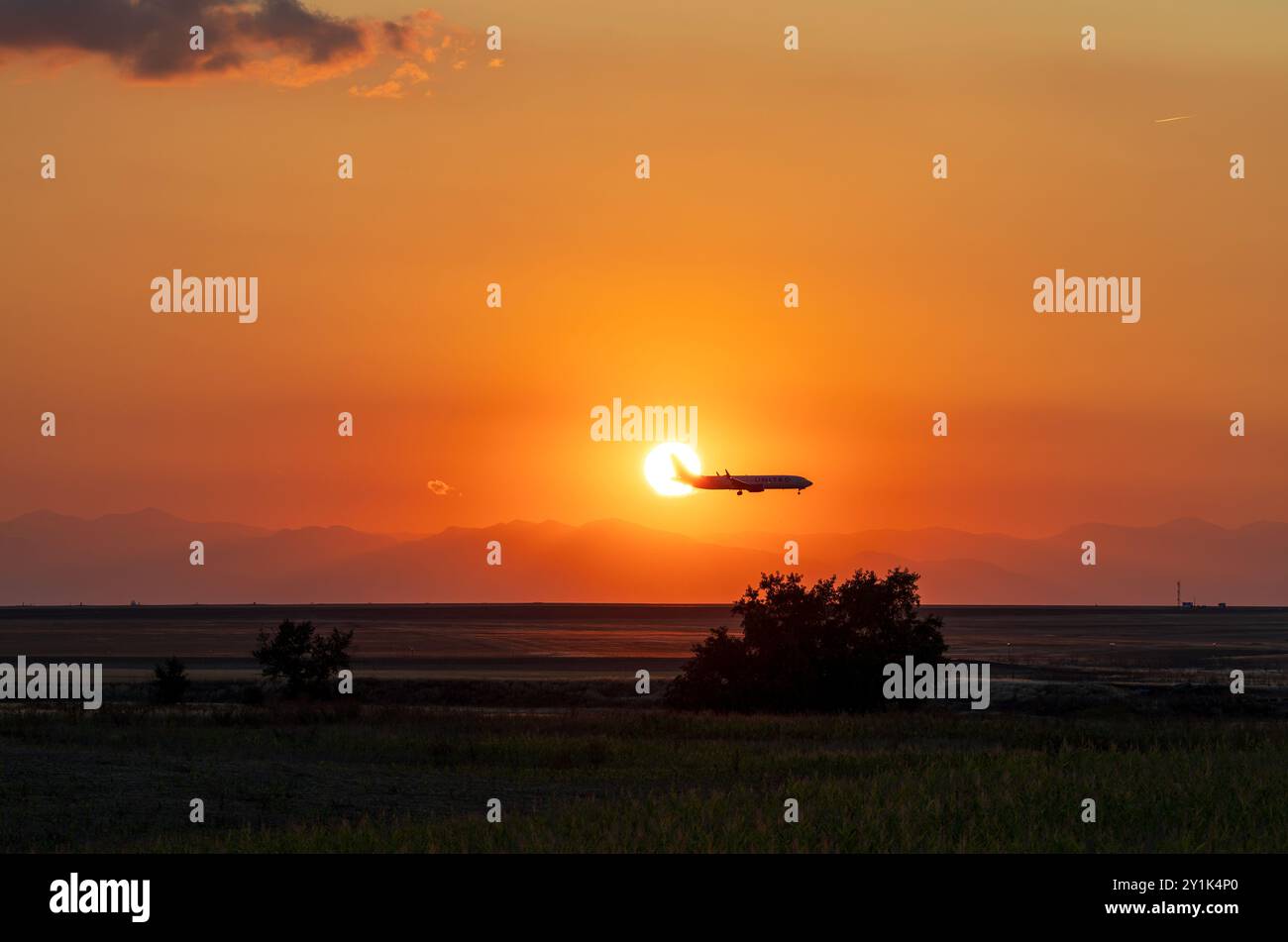 An airplane flying in the sunset sky above the Colorado prairies with ...