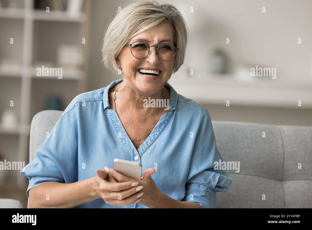 Happy mature woman laughing while using her smartphone Stock Photo - Alamy