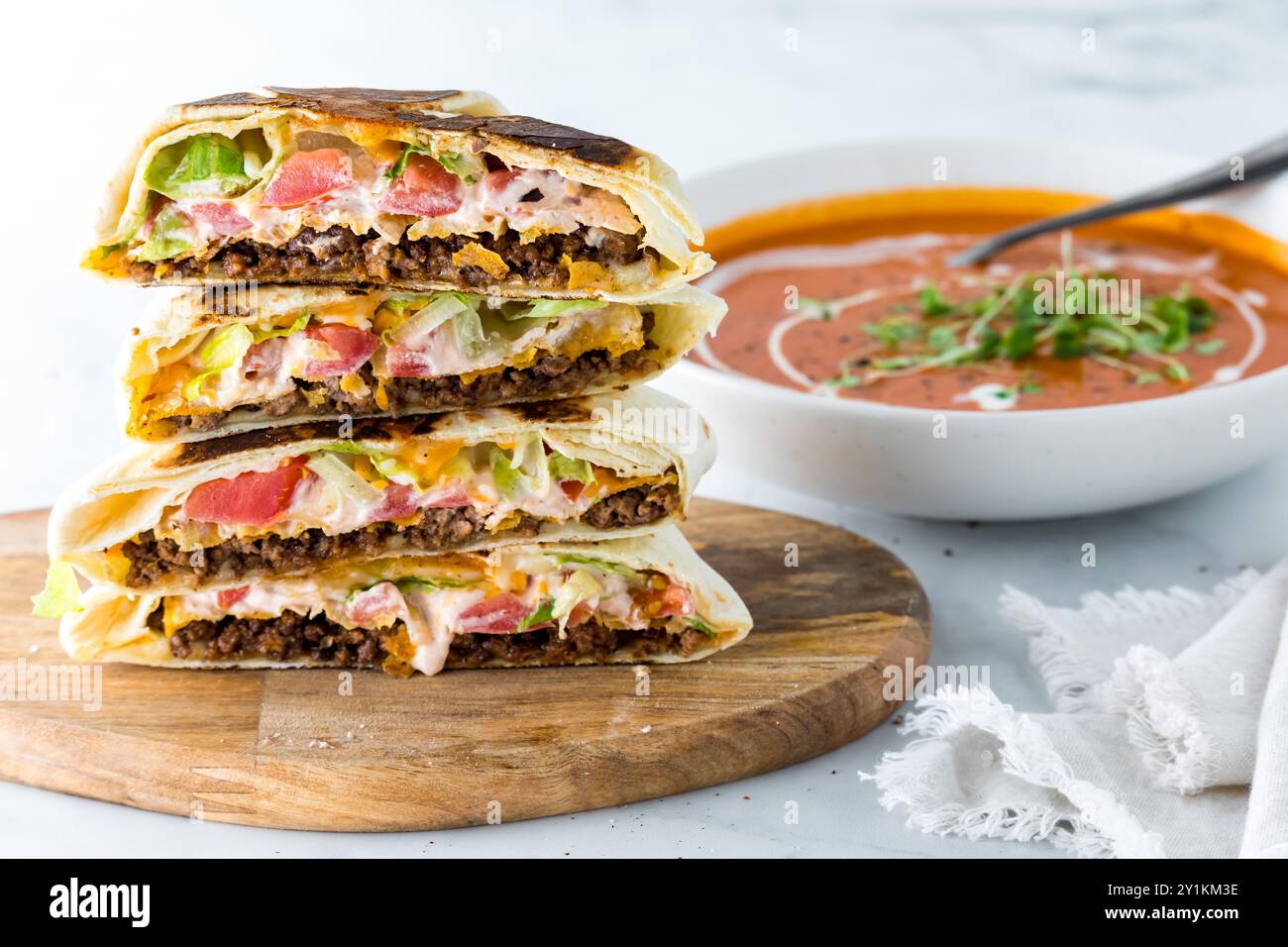 A stack of homemade crunch wraps with roasted red pepper soup in behind ...