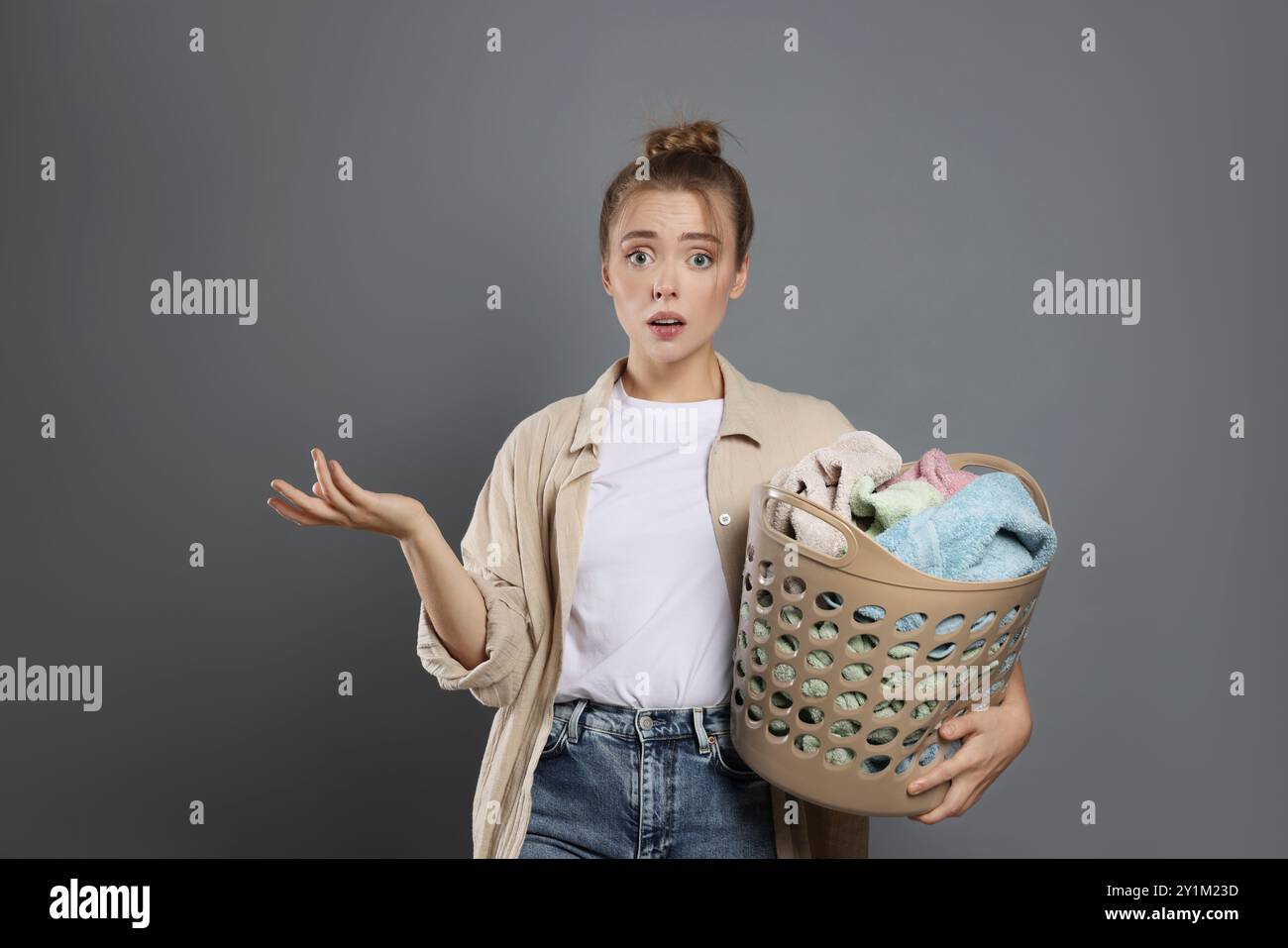 Tired housewife with basket full of laundry on grey background Stock ...