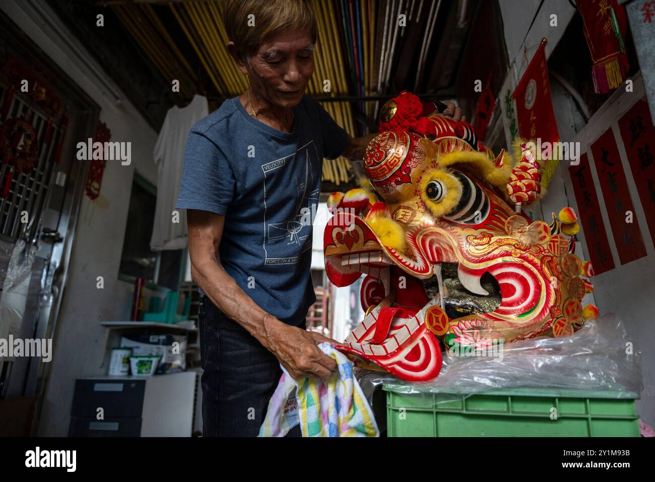 Villager Lo Yuet-ping cleans the head prop that's used in the ...