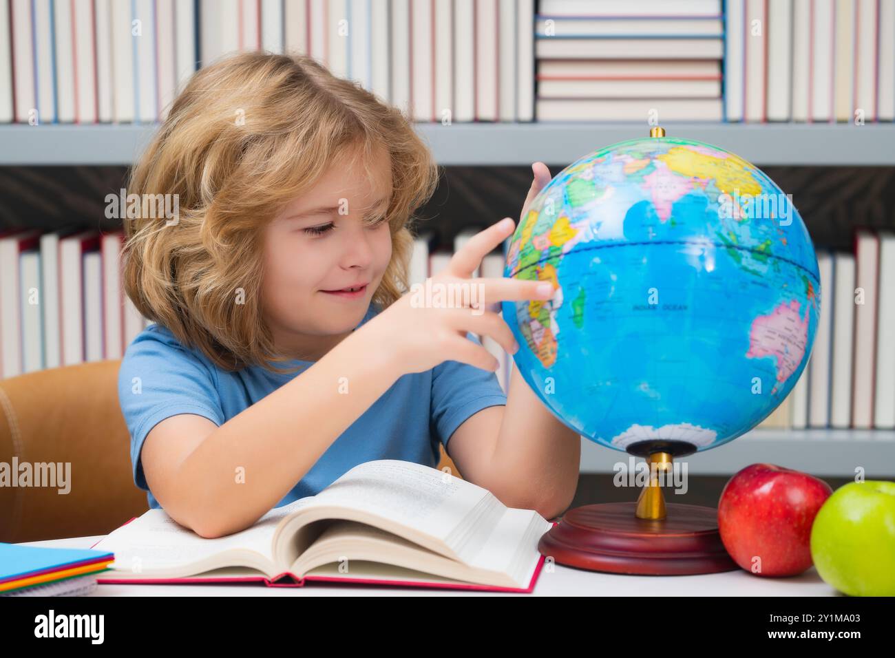 School boy looking at globe in library, geography lesson. School child ...